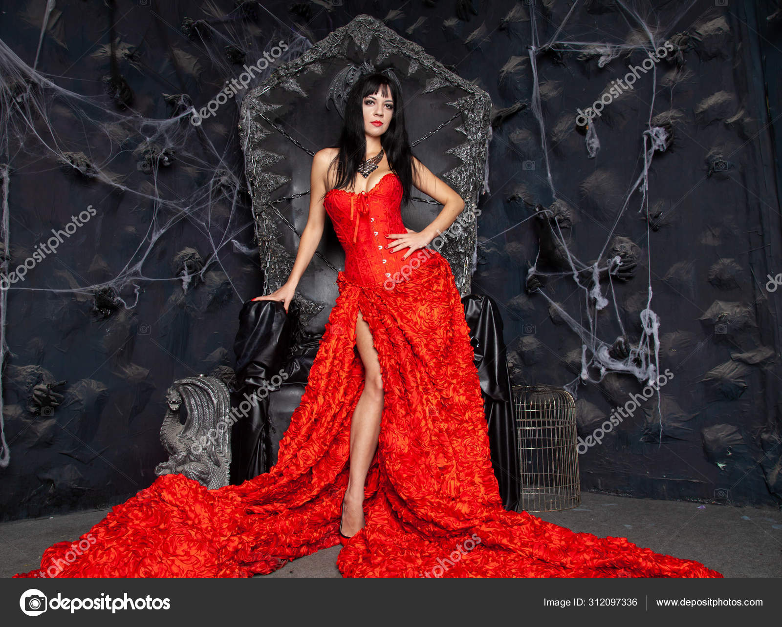 Beautiful vampire woman in red long dress near big black throne in the ...