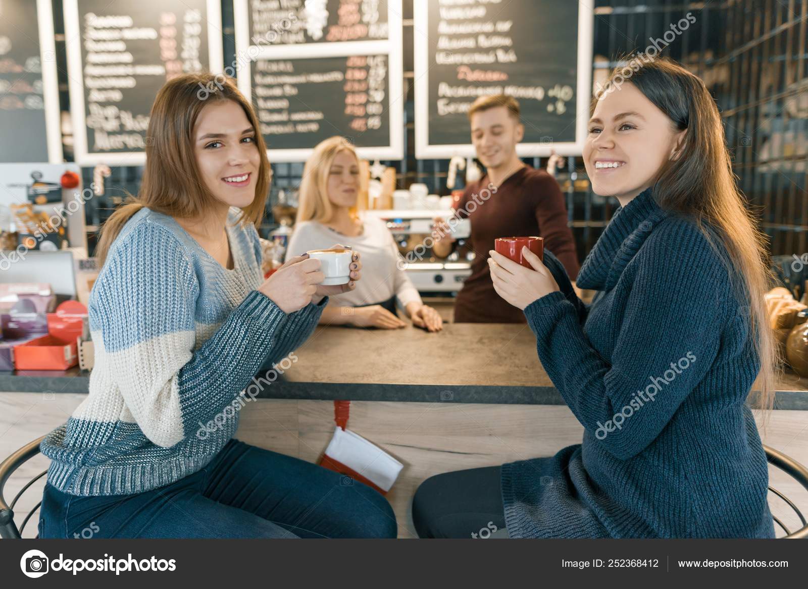 Young women drinking coffee in cafe, girls sitting near the bar counter ...