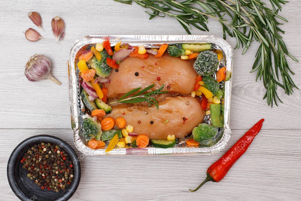 Un par de pechugas de pollo crudas o filete con verduras congeladas en ...