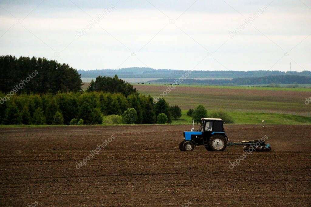 Un tractor grande con un arado arada un campo antes de la siembra de ...