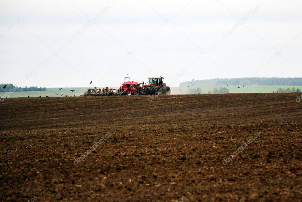 Un tractor grande con un arado arada un campo antes de la siembra de ...