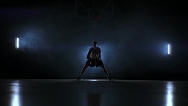 A man with a basketball on a dark basketball court against the backdrop ...
