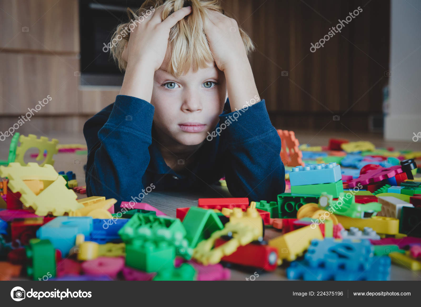 Sad child, stress and depression, exhaustion with toys scattered around ...