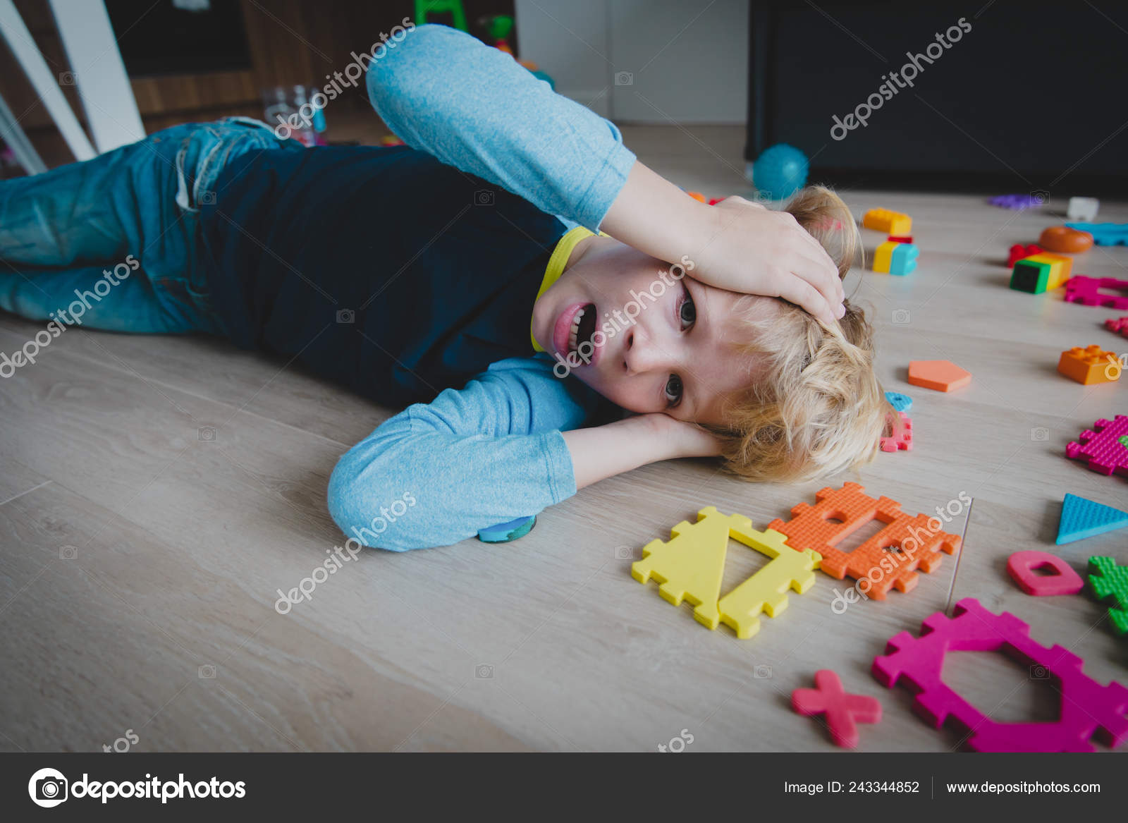 Sad young boy shouting with toys scattered around, child in stress ...