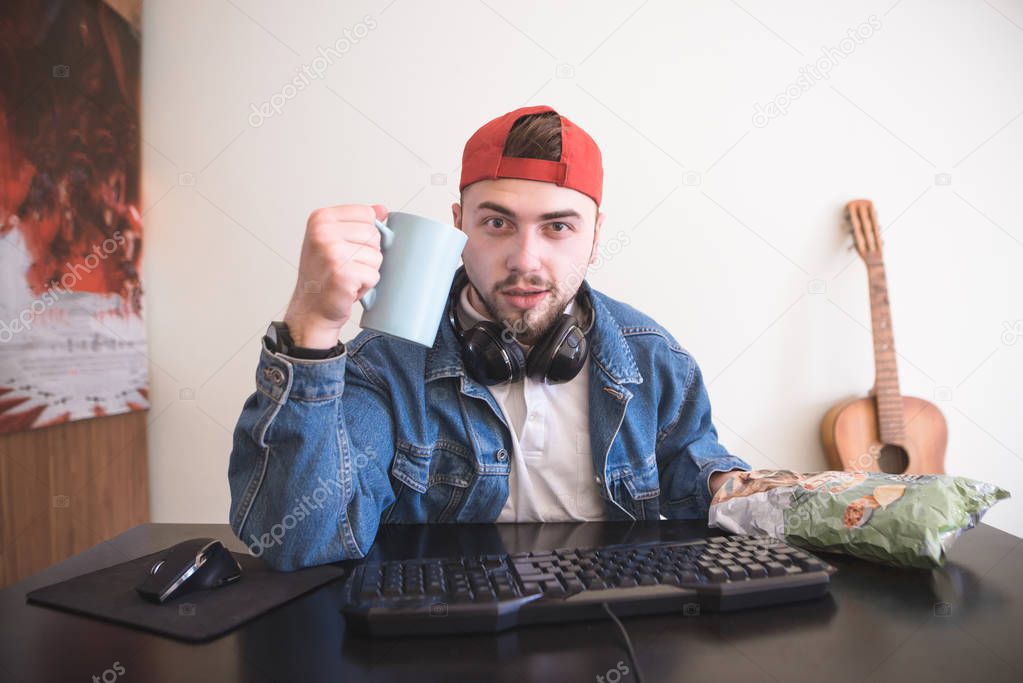 Gamer se sienta en una computadora en casa con una taza y merienda en ...