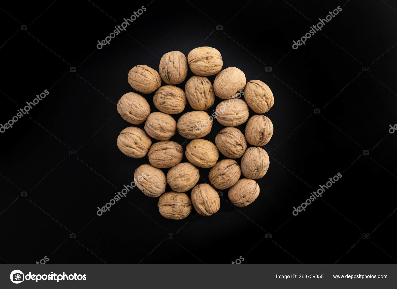 Walnuts in shell in the center on black surface, top view. Background ...