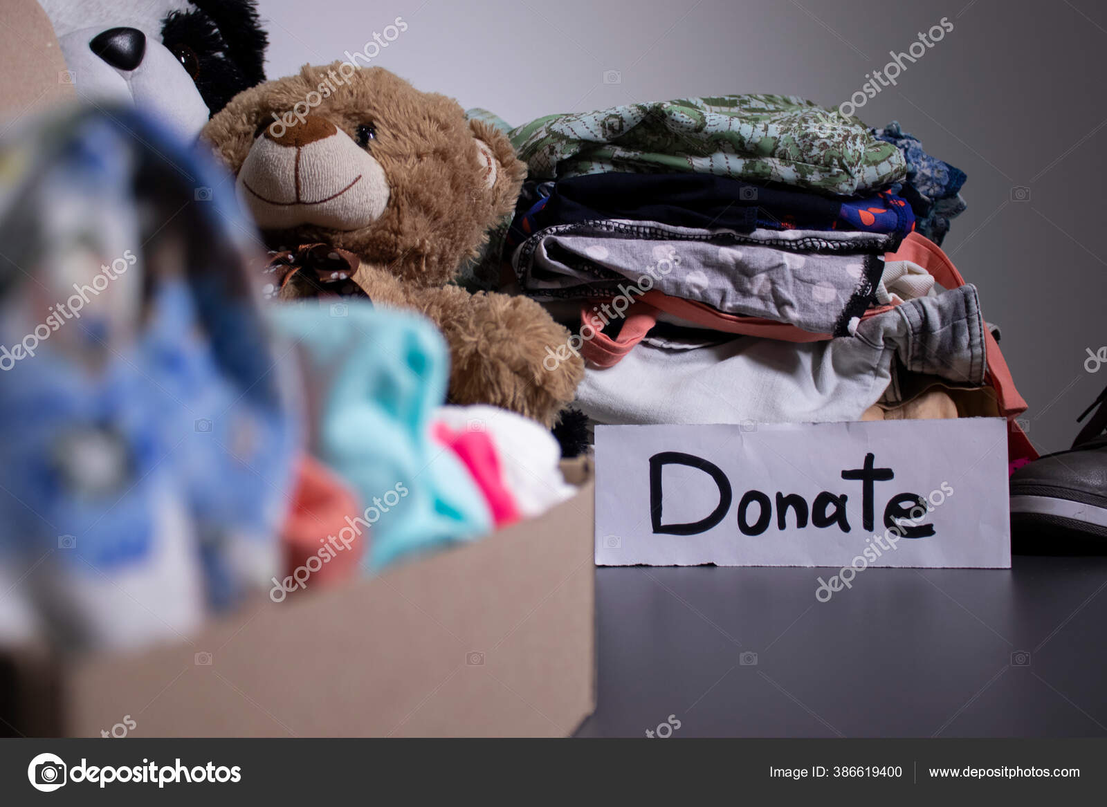 Donar signo escrito a mano con letras negras. Una caja con ropa y una ...