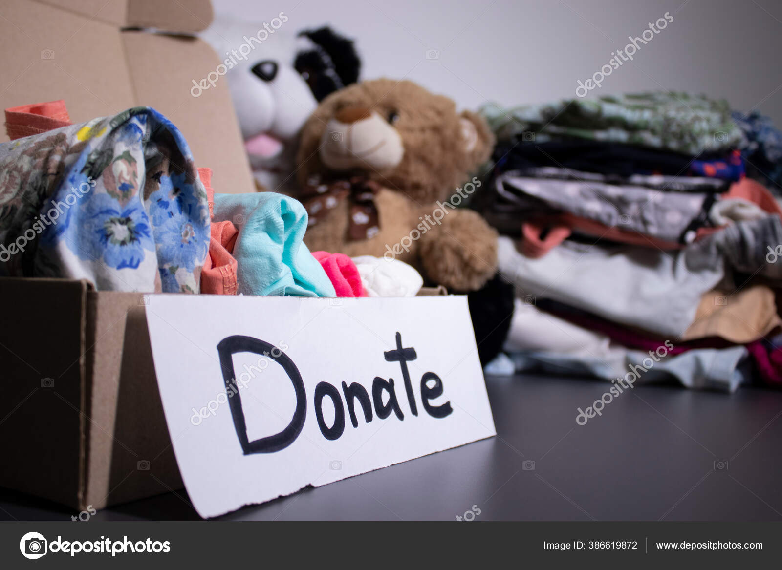 Donar signo escrito a mano con letras negras. Una caja con ropa y una ...