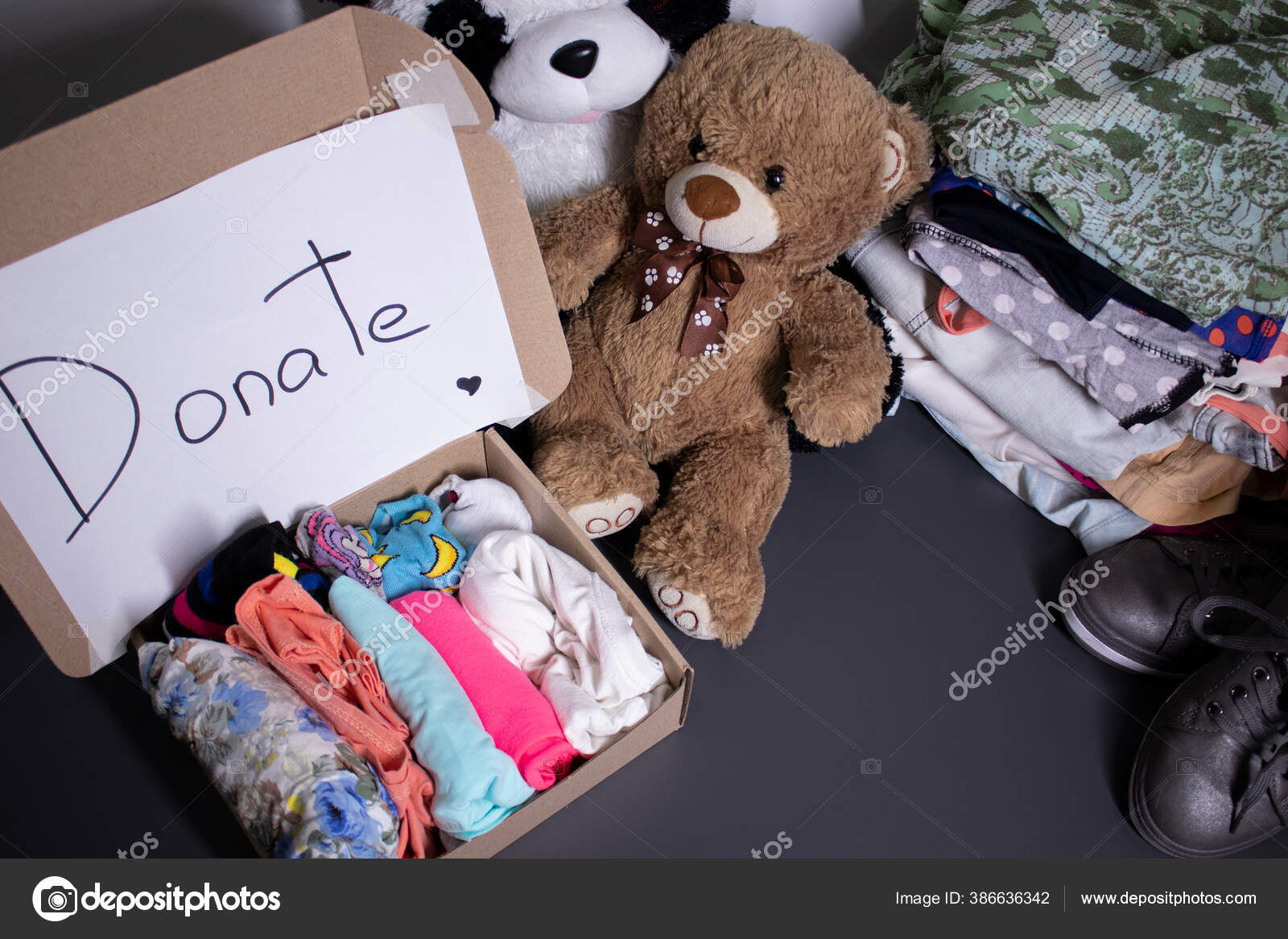 Donar signo escrito a mano con letras negras. Una caja con ropa y una ...