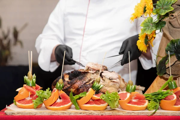 Show at restaurant: chief cook cuts into pieces freshly cooked pork ...