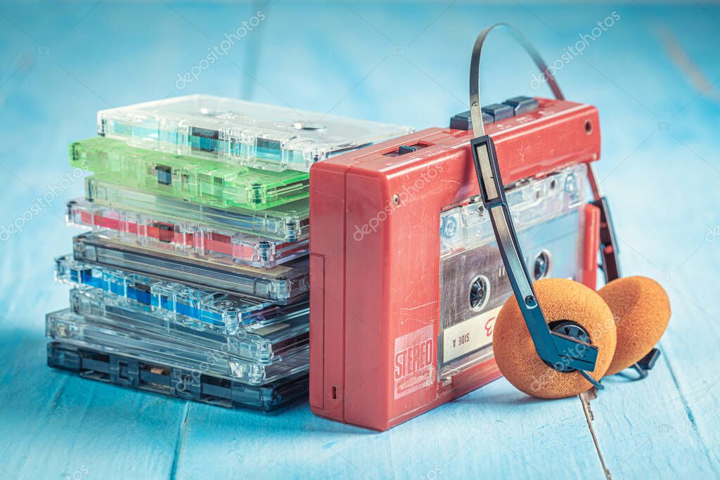 Cassette de audio vintage con auriculares y reproductor en mesa azul 2024