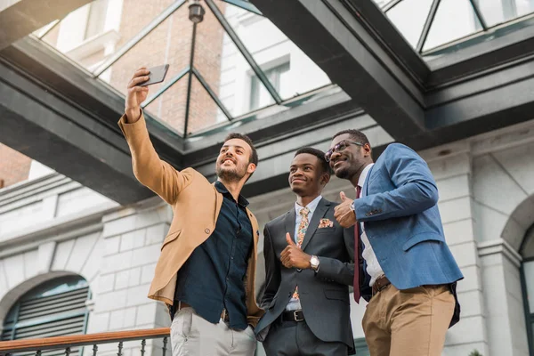 three young friendly men in suits are photographed on a smartphone ...