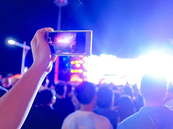 Hands of unidentified taking a photo with mobile smart phone of concert ...