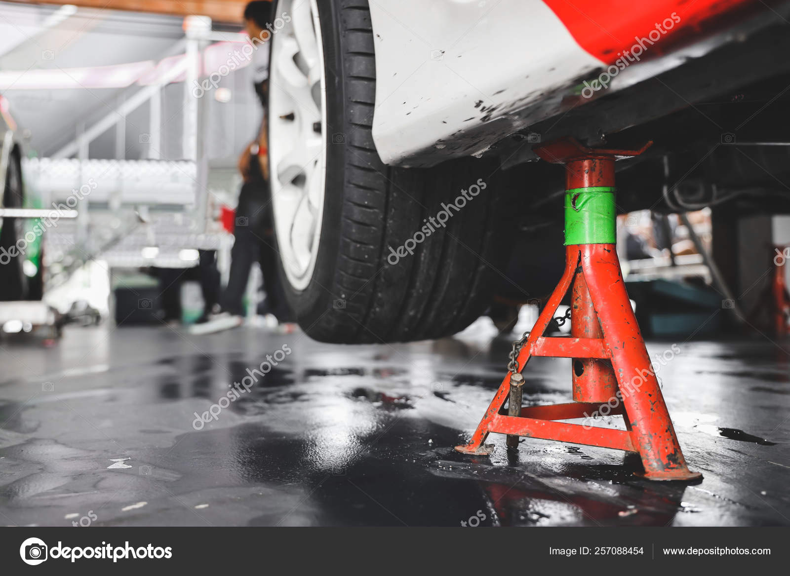 Maintenance car. Jacking up a car for changing tire in garage. — Stock ...