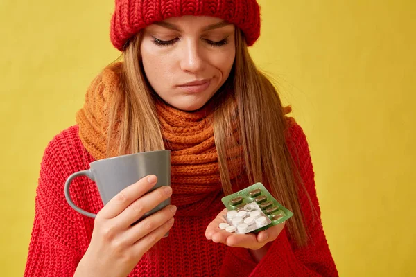 Sick woman holding pills and a cup in her hands. Image on yellow ...