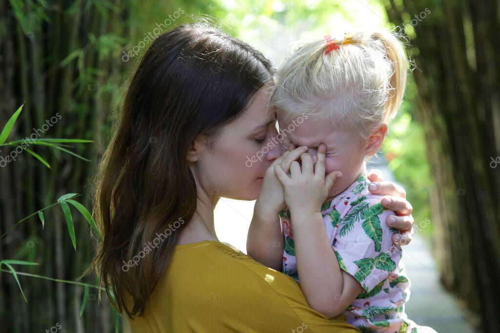 Joven madre abrazando a su pequeña hija llorando. Triste hija en brazos ...