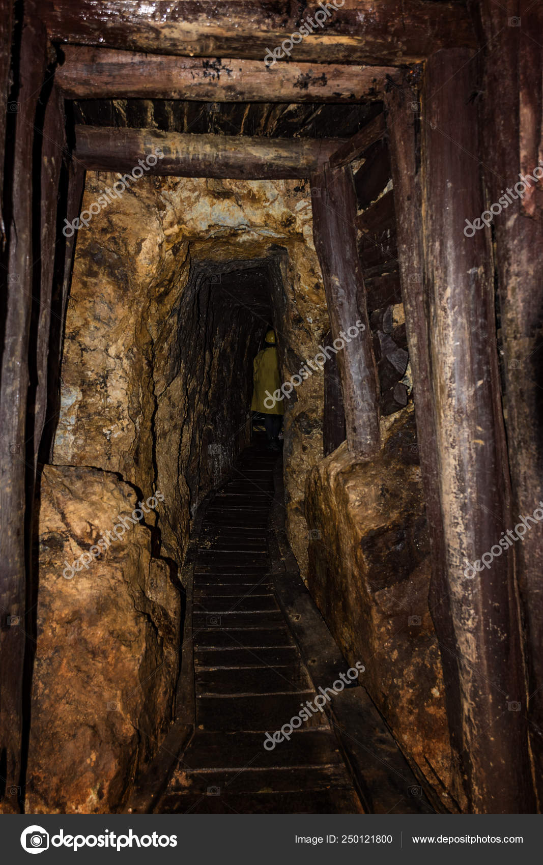 Old mine shaft with wooden timbering and person dressed in a min ...