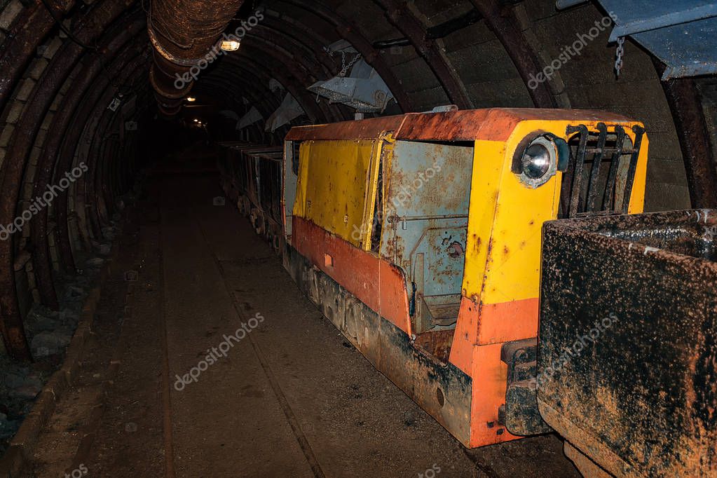 Tren minero metálico viejo y oxidado con vagones en túnel minero con 2023