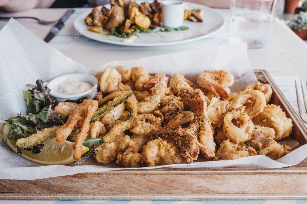 Frito misto frito mariscos en una bandeja de madera en un restaurante. 2024