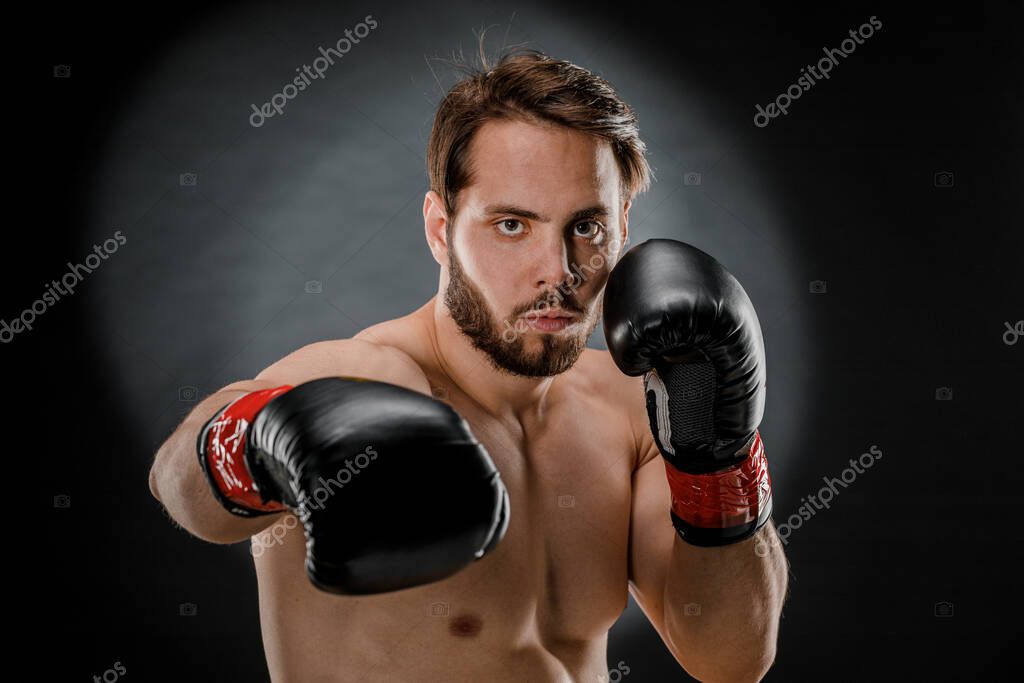 Un hombre con guantes de boxeo. Un hombre boxeando sobre un fondo negro ...