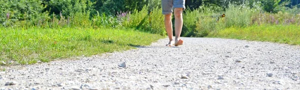 Close-up on the feet - walks across a pebble path in the woods and ...