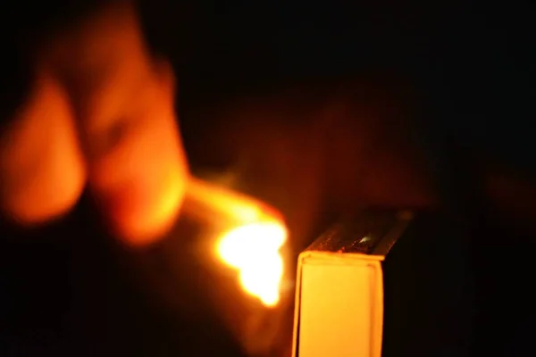 Igniting a match in the dark on a matchbox - Close-up of a lighting ...