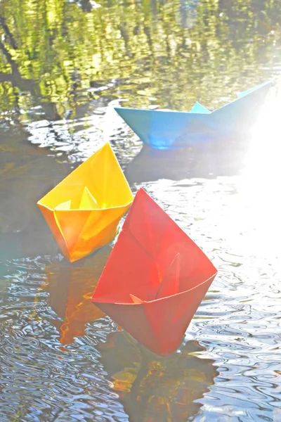 Different colored paper ships swim in a small brook on the surface of ...