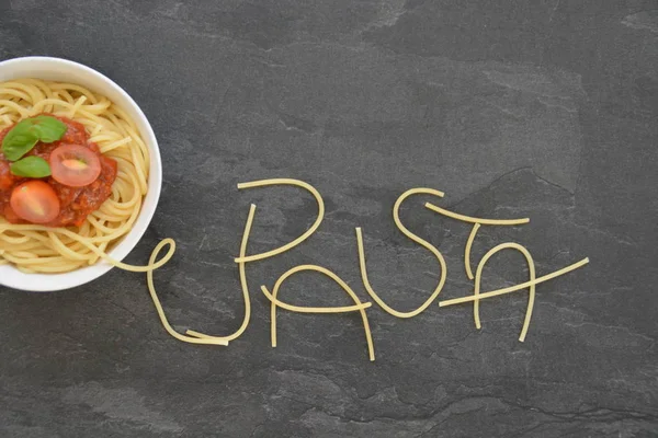 With spaghetti, the word pasta was written on a dark marble surface ...