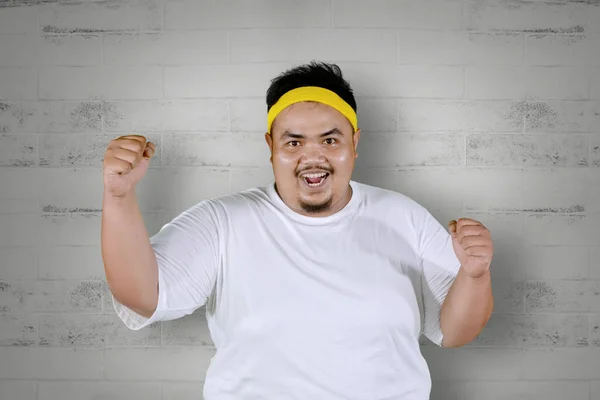 Young obese man carrying fat word on studio - Stock Image - Everypixel