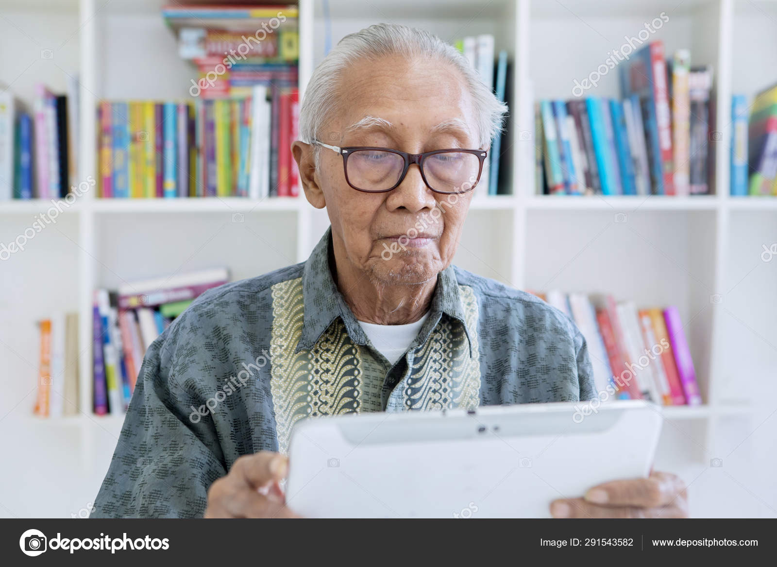 Old man using a digital tablet in the library Stock Photo by ...