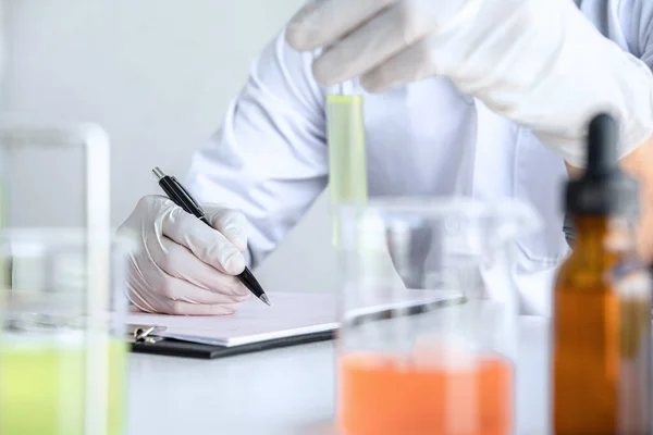 Scientist or medical in lab coat holding test tube with reagent, mixing ...