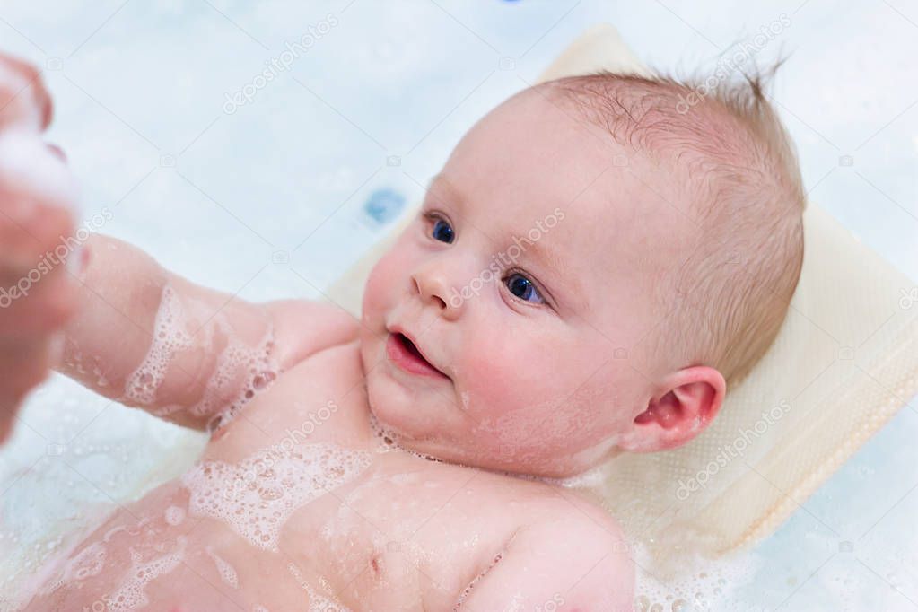 Niño de 6 meses tomando un baño. Un niño pequeño en una bañera. Lavado ...