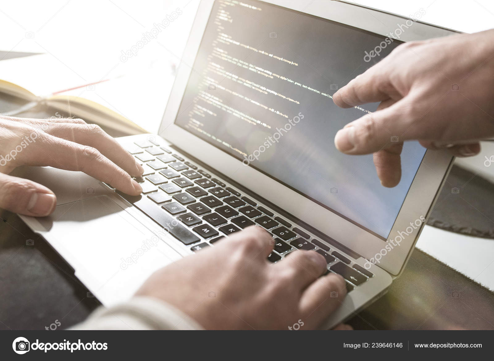 Person working on laptop computer while other is pointing at monitor ...