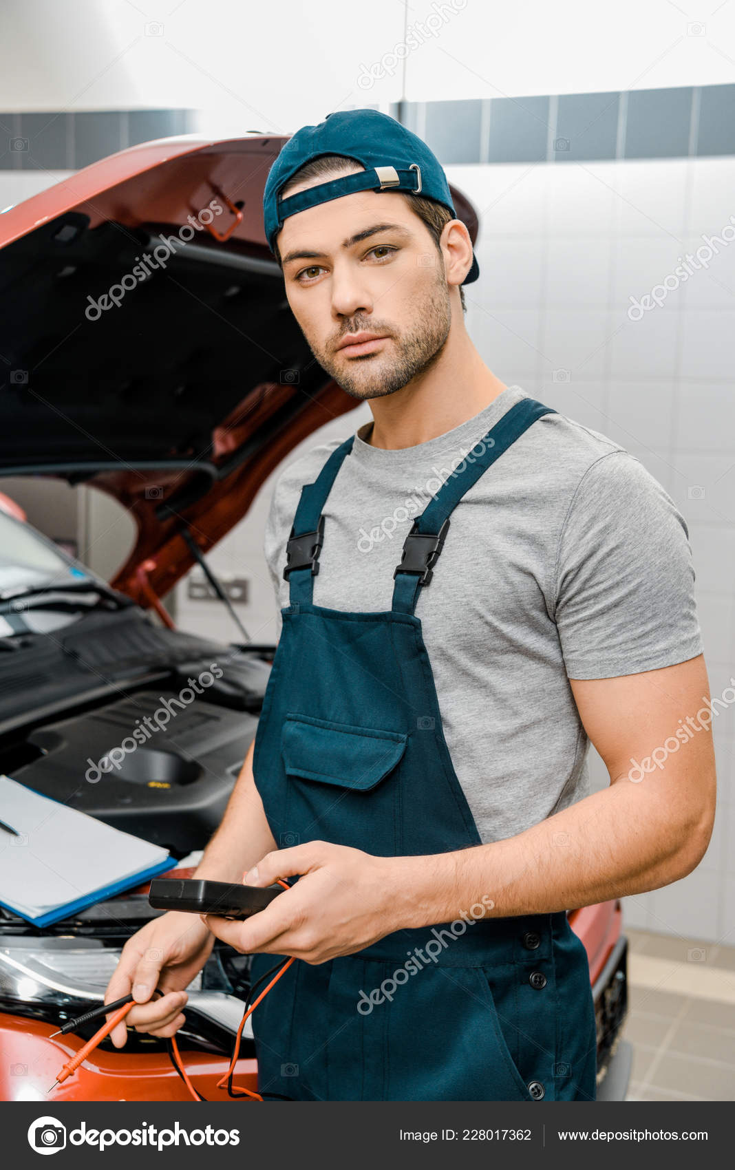 Portrait Auto Mechanic Holding Multimeter Voltmeter Car Battery Voltage ...