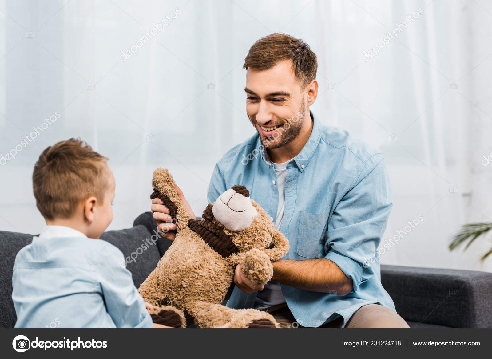 Smiling Father Son Sitting Sofa Holding Teddy Bear Living Room — Free