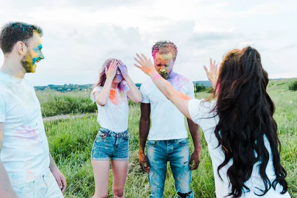back view of woman throwing in air holi paints near multicultural ...
