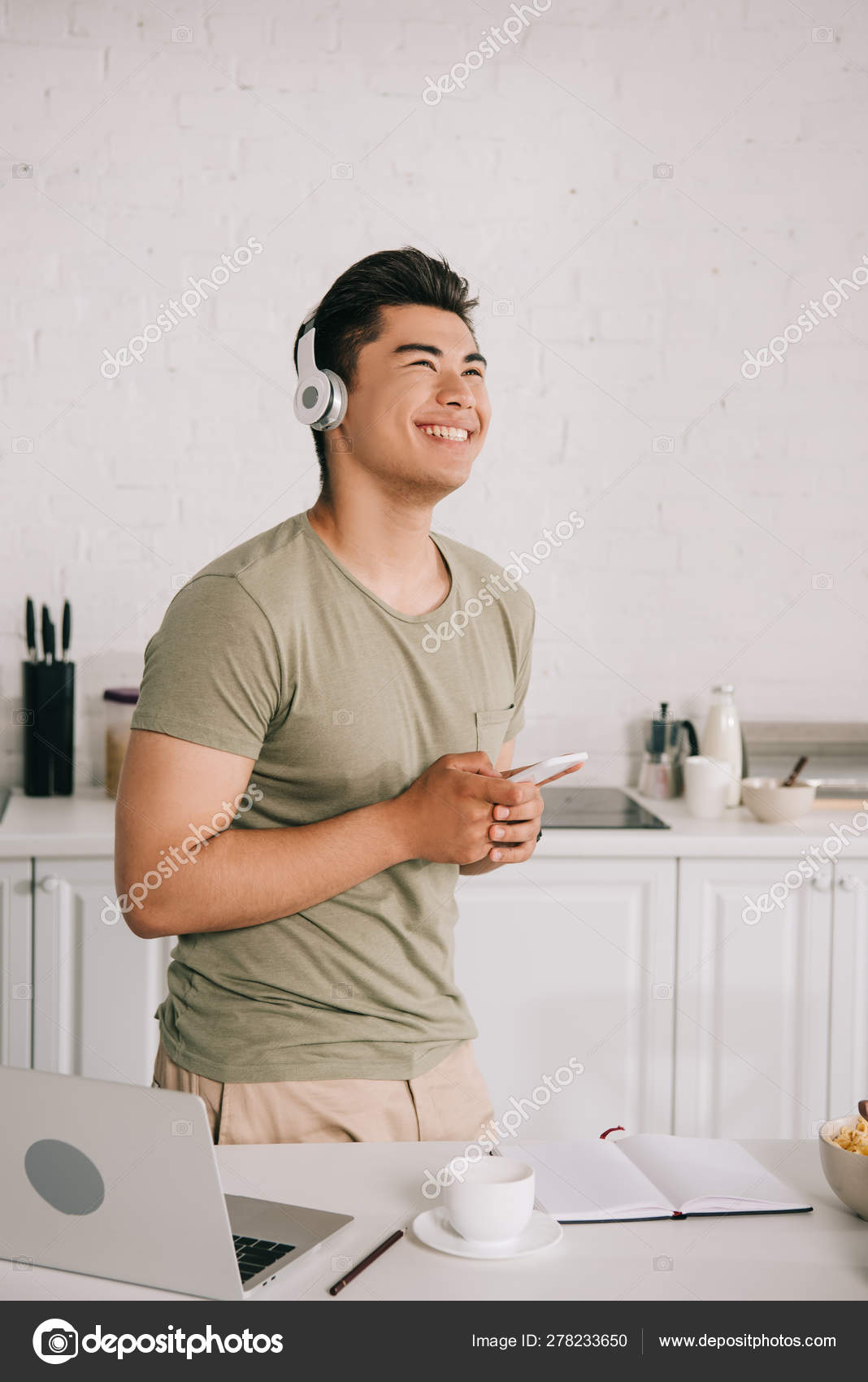 Cheerful Asian Man Listening Music Hedphones While Holding Smartphone