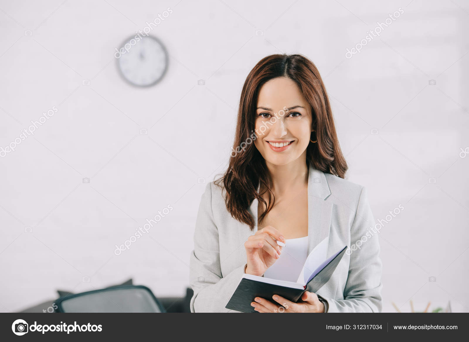 Beautiful Smiling Secretary Looking Camera While Writing Notebook ...