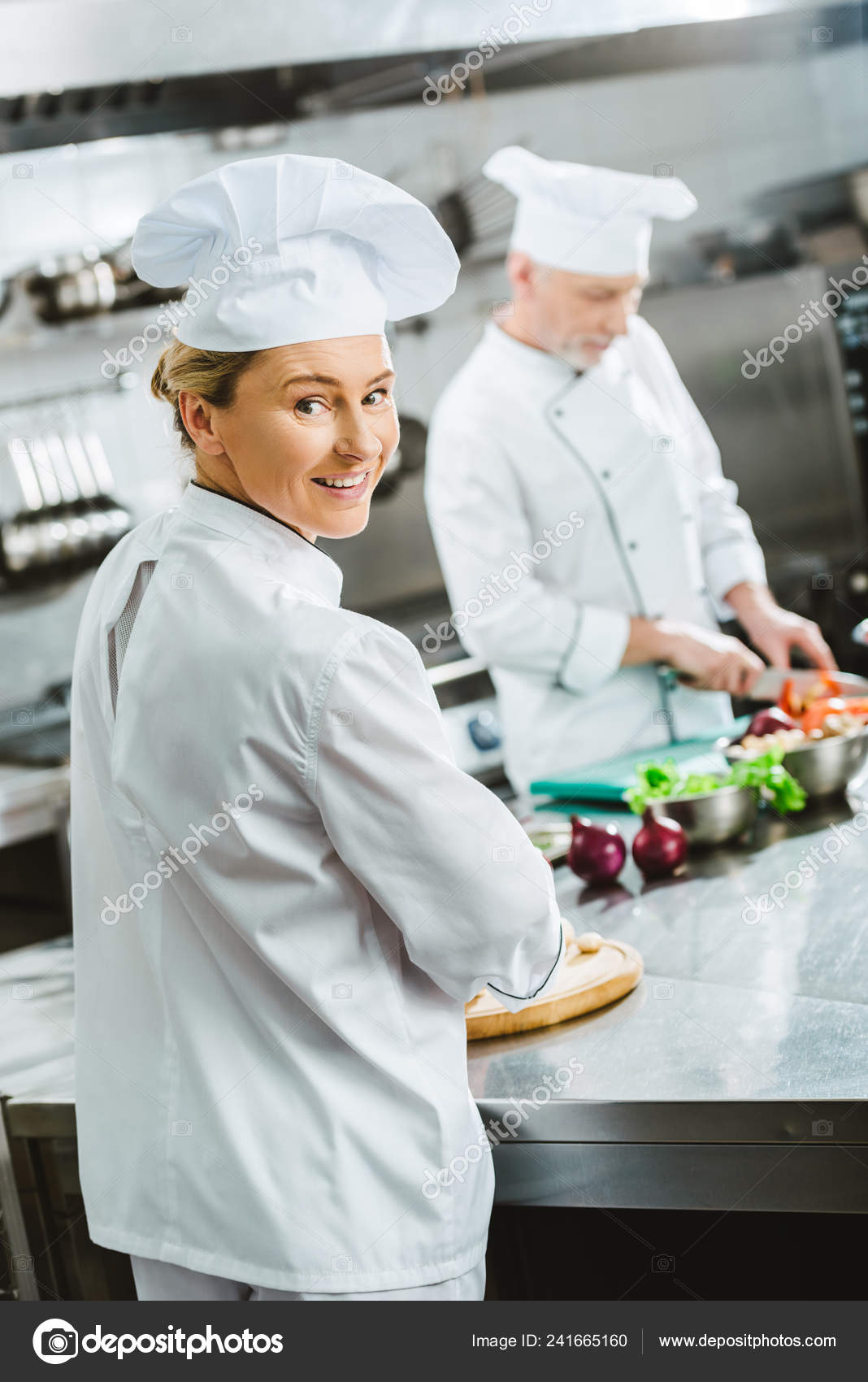 Hermosa Mujer Chef Mirando Cámara Sonriendo Mientras Cocina Con Colega ...