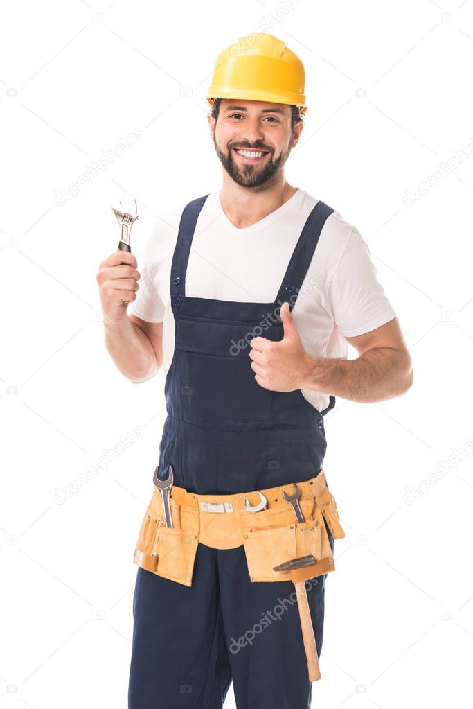 guapo feliz obrero sosteniendo la llave inglesa y sonriendo a la cámara ...