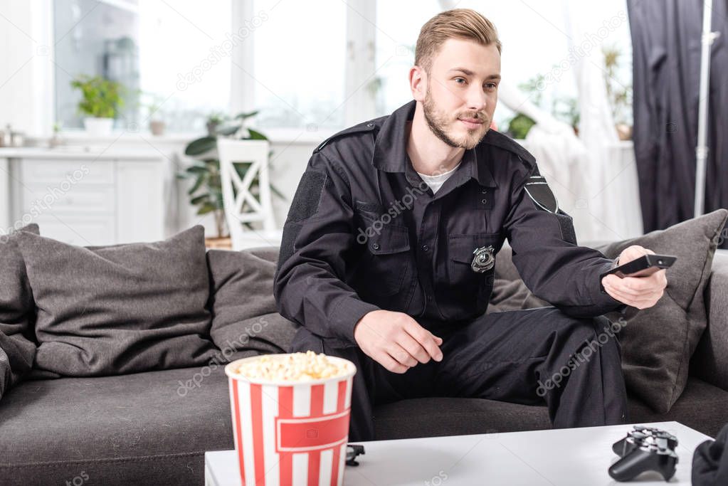 hombre en uniforme de policía sentado en el sofá y viendo la película 2023 hombre en uniforme de policía sentado en el sofá y viendo la película 2023