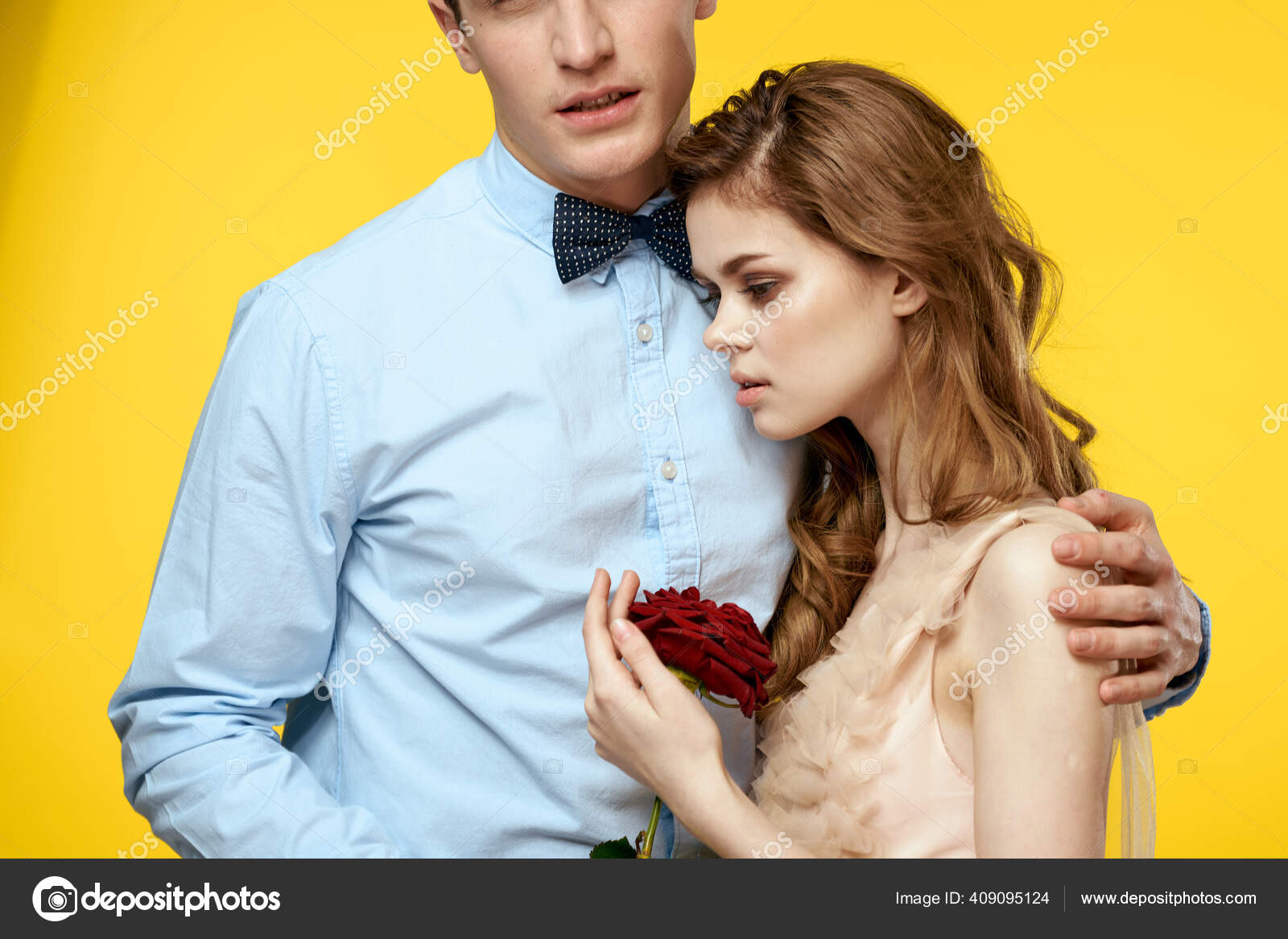 A romantic man hugs a woman in a red dress with a rose in his hand on a ...