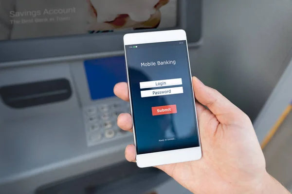 Withdraw money from an ATM without using a credit card. Person holding a phone with a login ...
