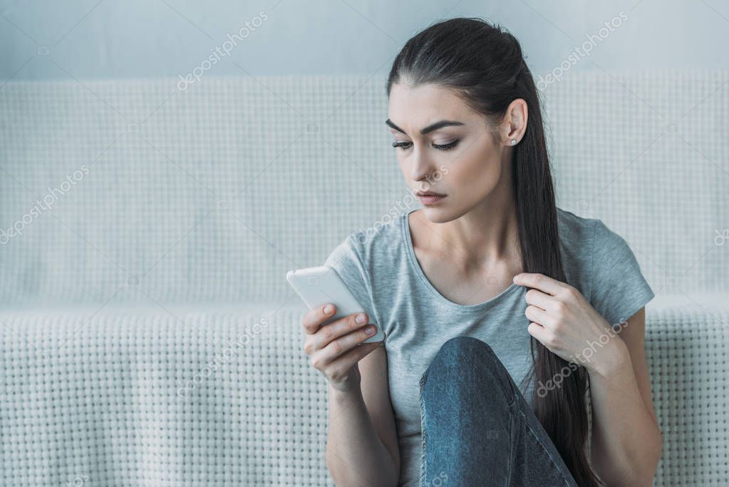 mujer joven molesta usando el tel fono inteligente mientras est sentado en casa 2024