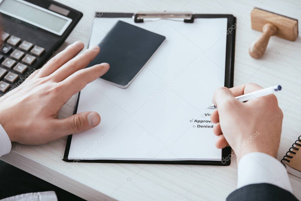 vista recortada del hombre poniendo señal de cheque en el documento con ...