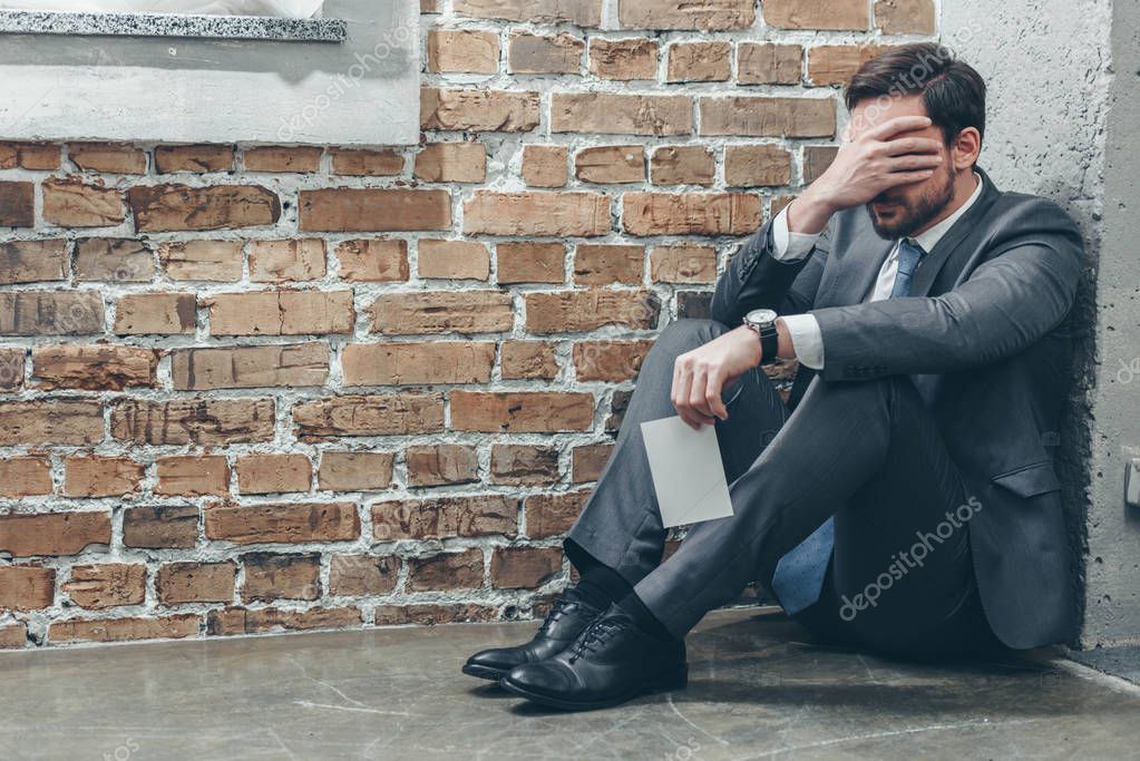 hombre molesto sentado en el suelo en la esquina, sosteniendo la foto y ...