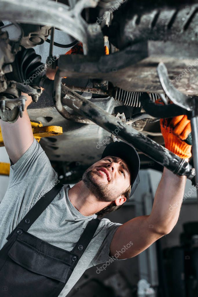 obrero profesional en uniforme reparando coche en taller mecánico 2024