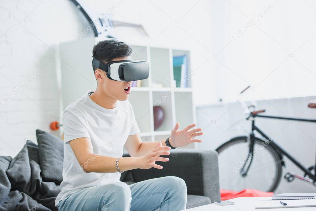 emocional joven asiático hombre sentado en sofá y usando virtual ...