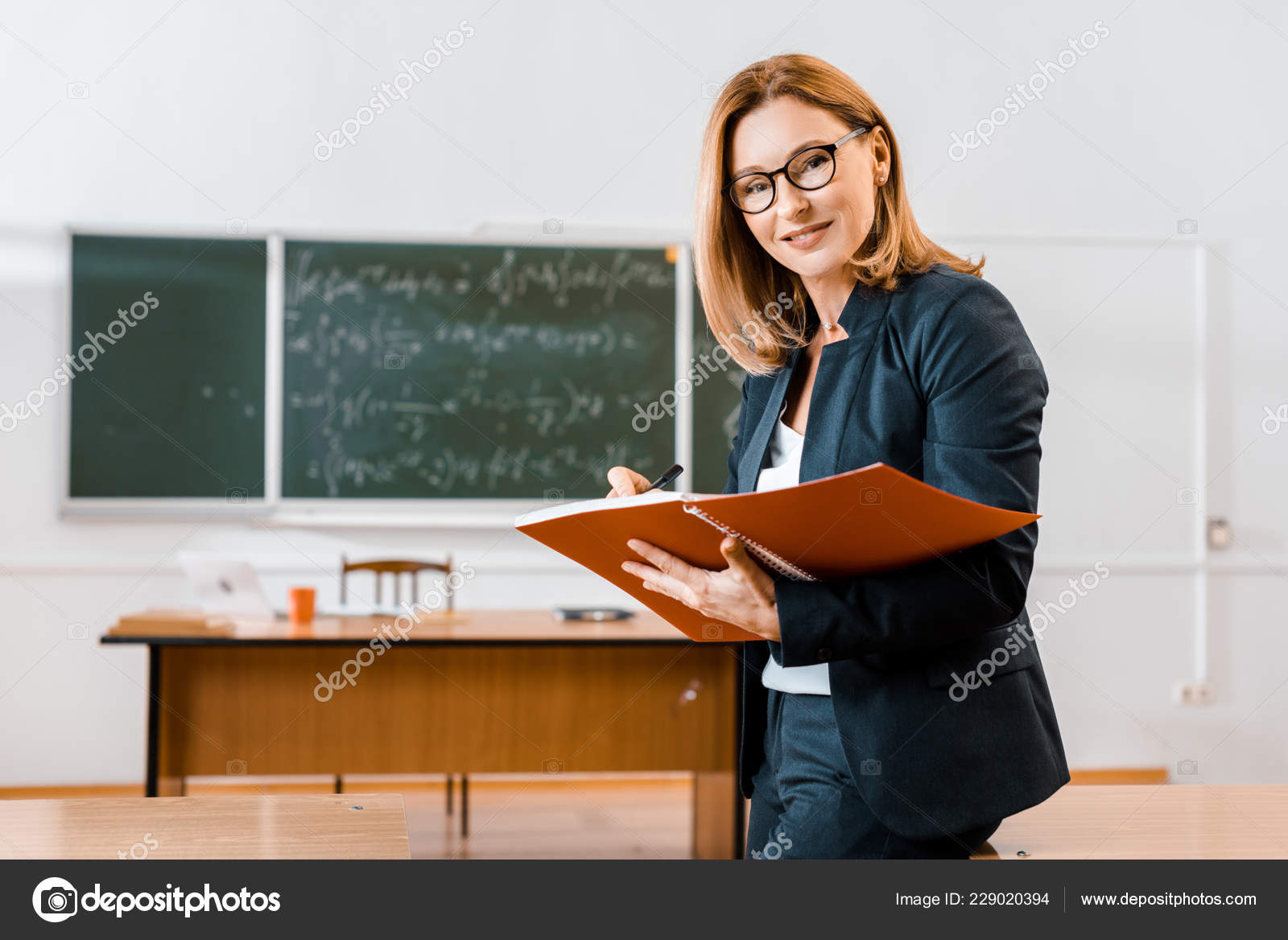Beautiful Female Teacher Formal Wear Writing Notebook Looking Camera ... Beautiful Female Teacher Formal Wear Writing Notebook Looking Camera ...
