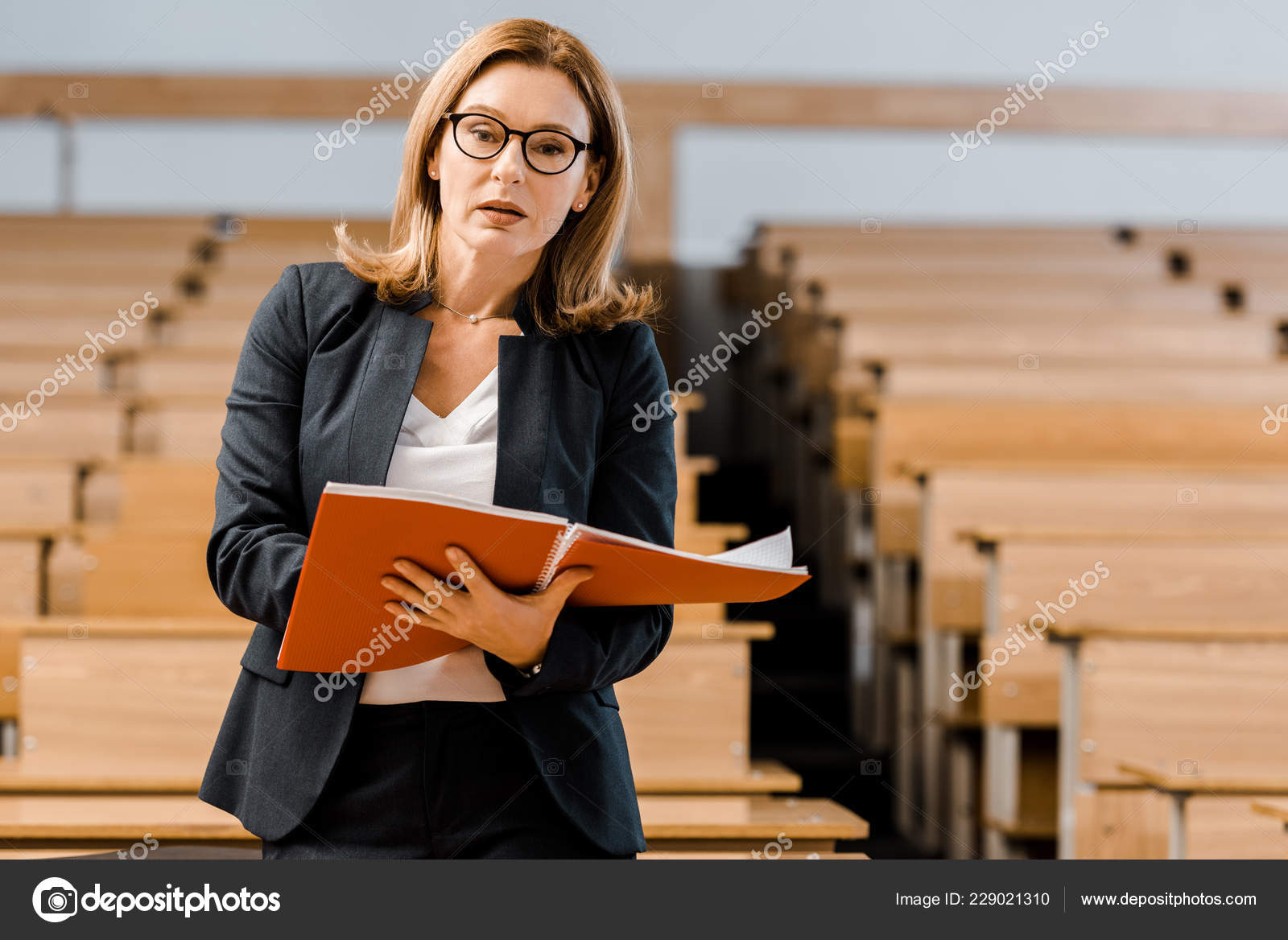 Female University Professor Holding Journal Looking Camera Classroom ...
